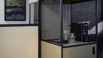 Quarto de hotel com cama, máquina de café, vitrine de vidro e bolsa na parede.