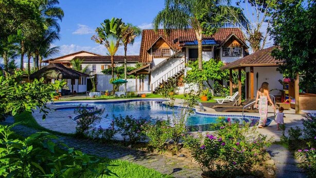 Um resort com piscina, palmeiras e área externa coberta.