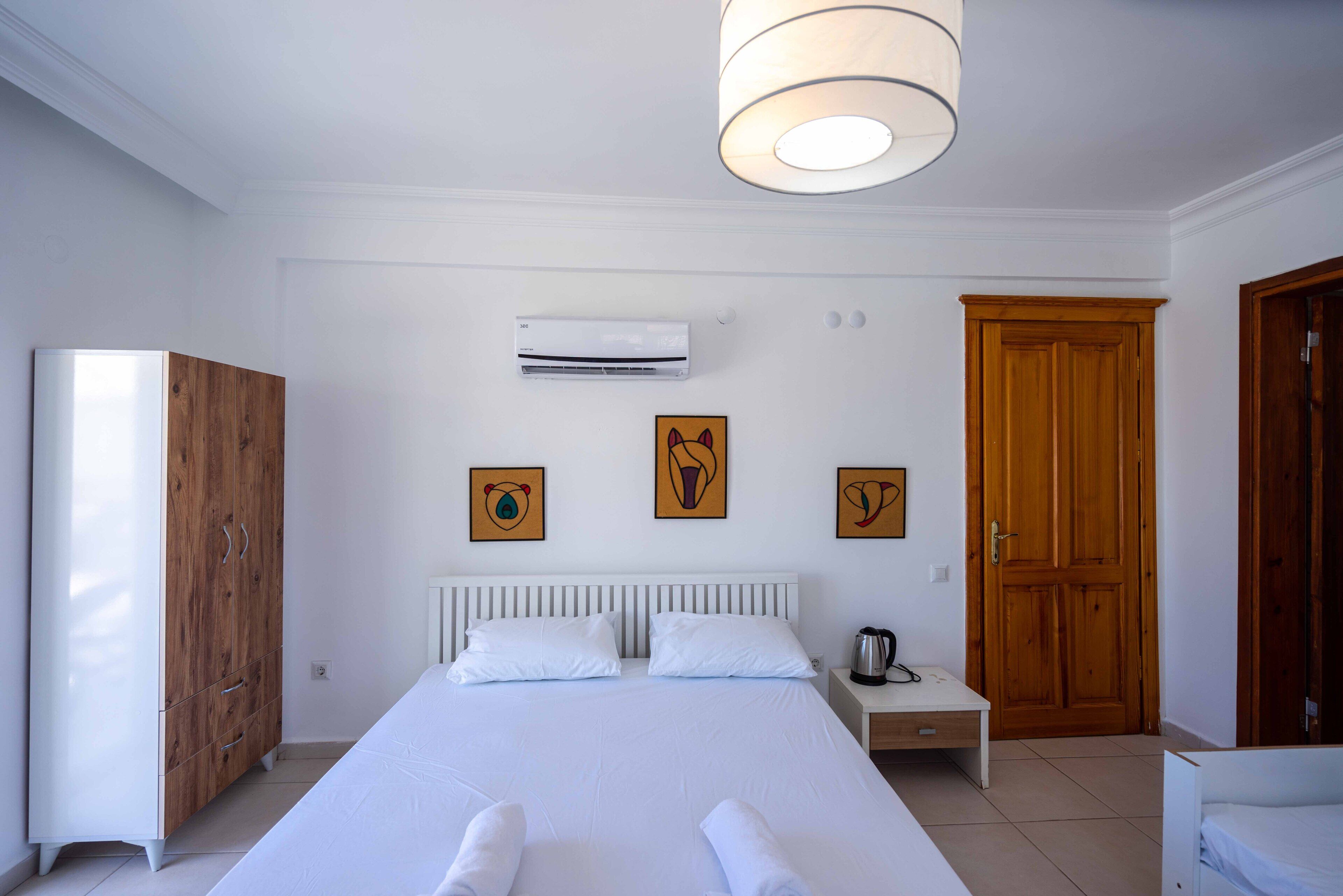Quarto com cama, mesa de cabeceira, guarda-roupa e uma pintura na parede.