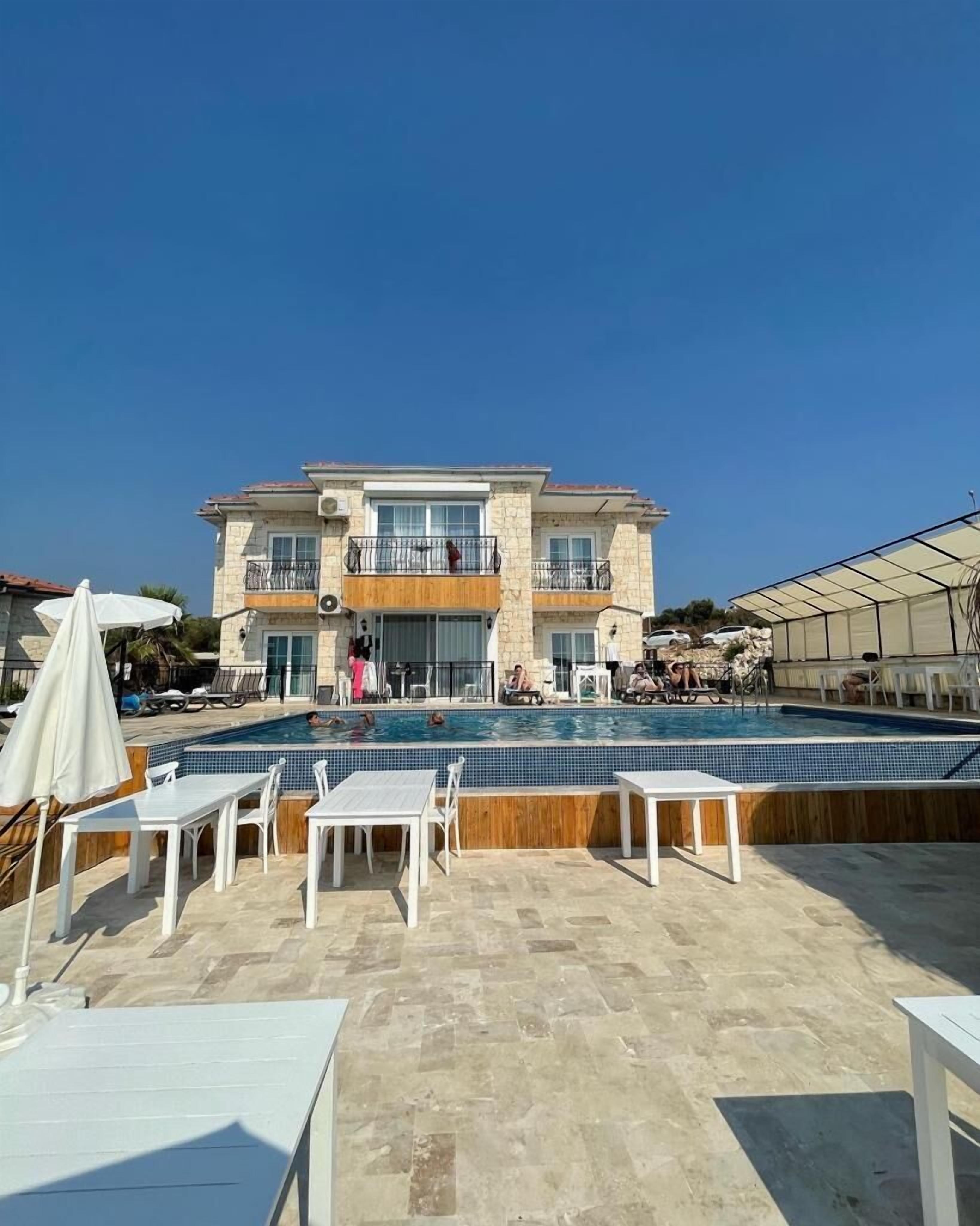 Um hotel com piscina, área de estar externa e espaço coberto.