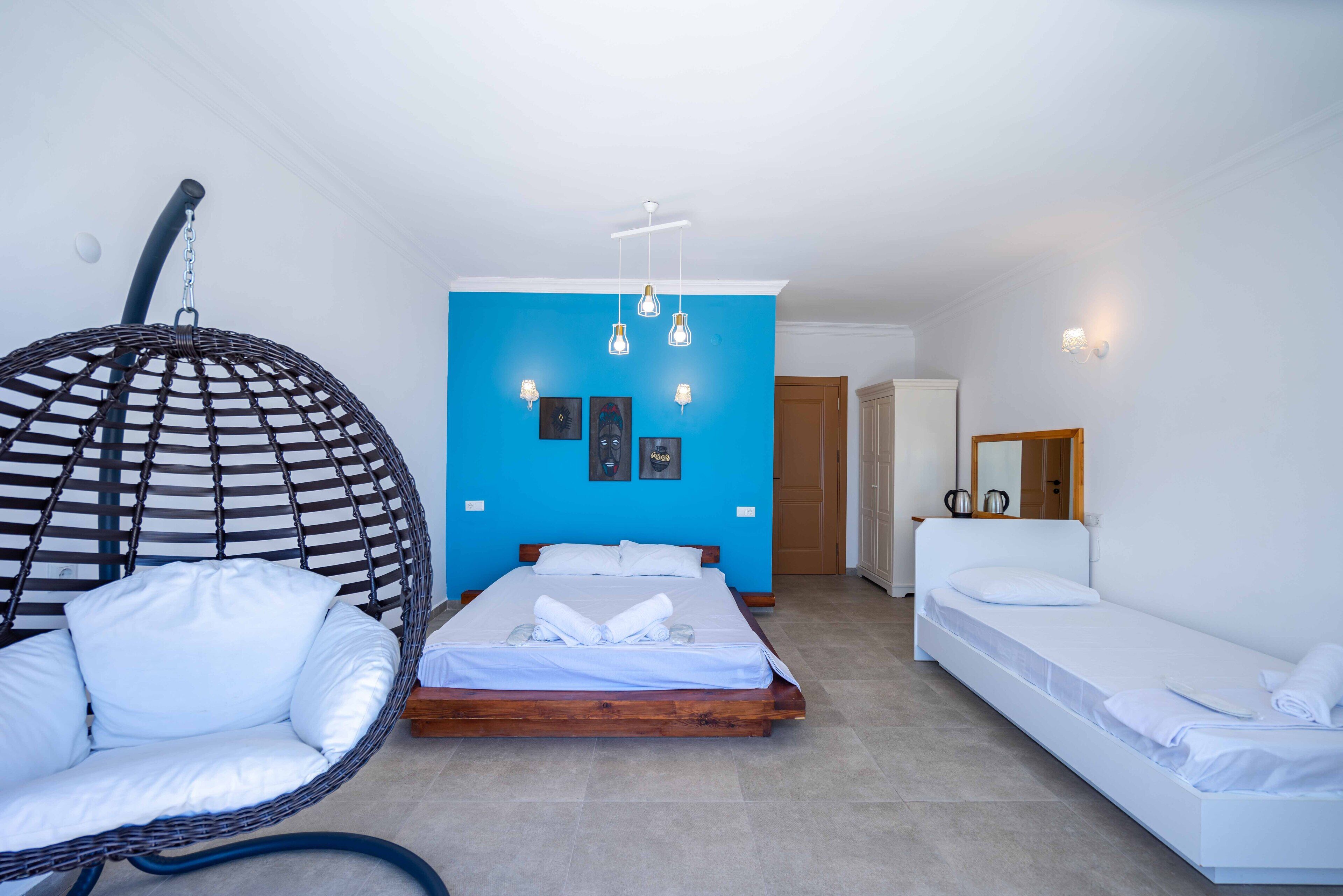 Um quarto com uma cama, uma cadeira suspensa e um sofá.