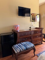 Quarto com uma cama, penteadeira, televisão e um pequeno aquecedor.