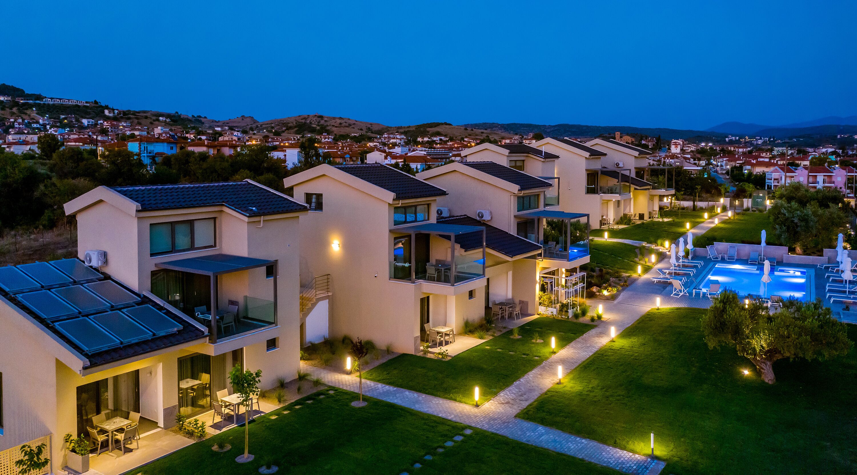 Um complexo residencial moderno com várias casas de dois andares, piscina e painéis solares.
