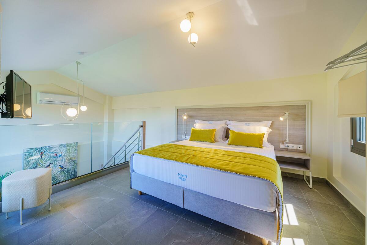 Quarto de hotel moderno com uma cama grande, um espaço de estar pequeno e vista para o exterior.