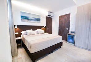 Quarto moderno com cama grande, luminárias de cabeceira, um quadro, ar-condicionado, guarda-roupa e um eletrodoméstico em uma mesa lateral.