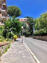 Uma rua calma no centro da cidade, com calçada, postes de iluminação e uma variedade de edifícios residenciais.