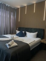 Quarto de hotel com uma cama grande, cabeceira e mesa de cabeceira.