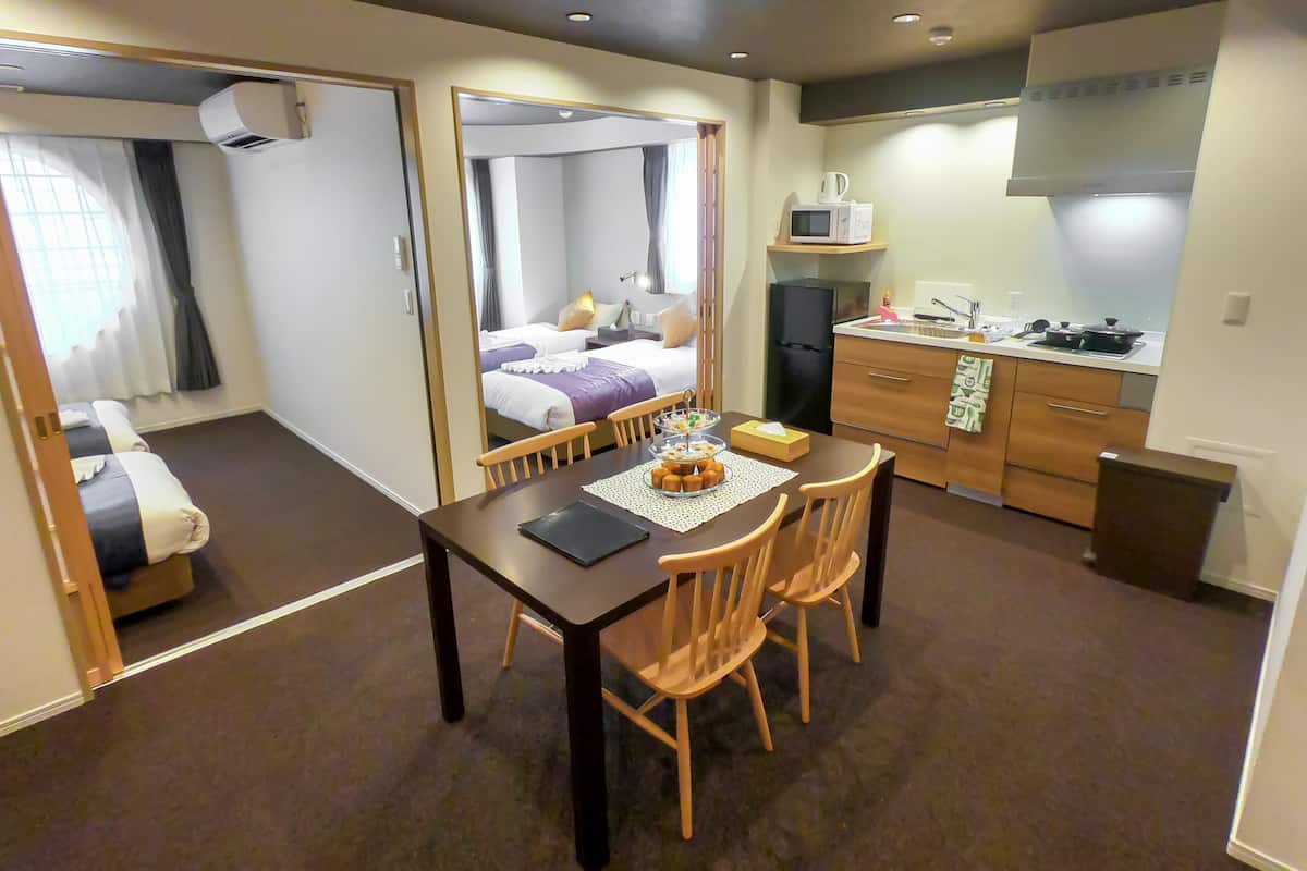 Quarto de hotel compacto com área de refeições, cozinha compacta e quarto separado.