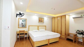 Quarto com cama, escrivaninha, cadeira, guarda-roupa e uma pequena mesa com flores.