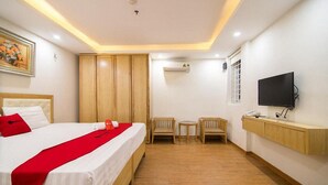 Quarto de hotel com cama, televisão, escrivaninha e cadeira.