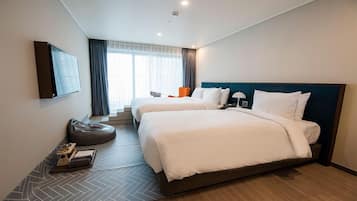 Quarto de hotel com duas camas, televisão, secretária e uma cadeira.