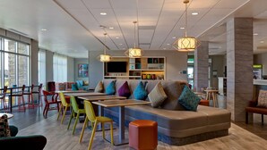 Uma área de estar moderna com sofá, cadeiras coloridas, mesa de madeira e iluminação pendente.