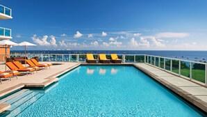 Uma piscina com espreguiçadeiras e vista para o oceano.