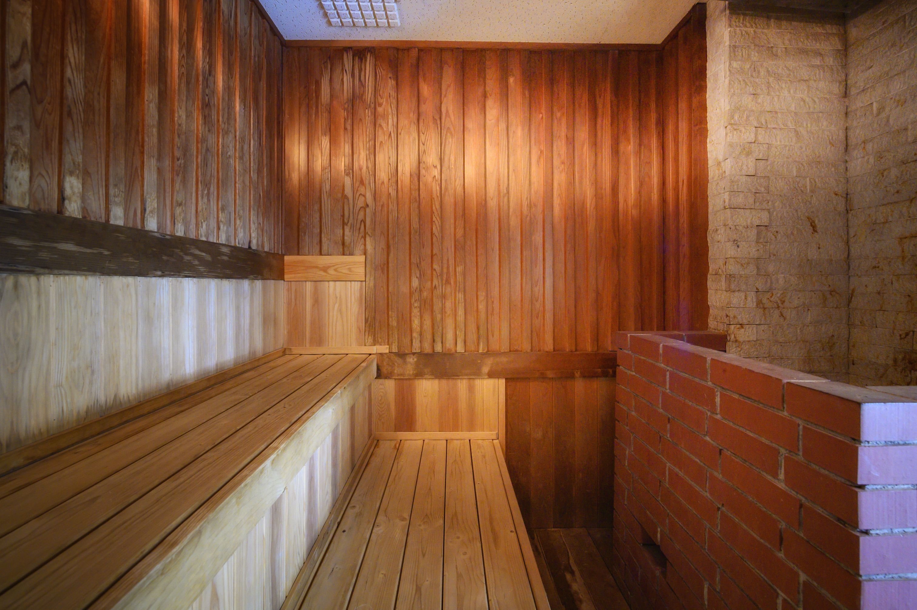 Uma sauna com bancos de madeira e parede de tijolos.