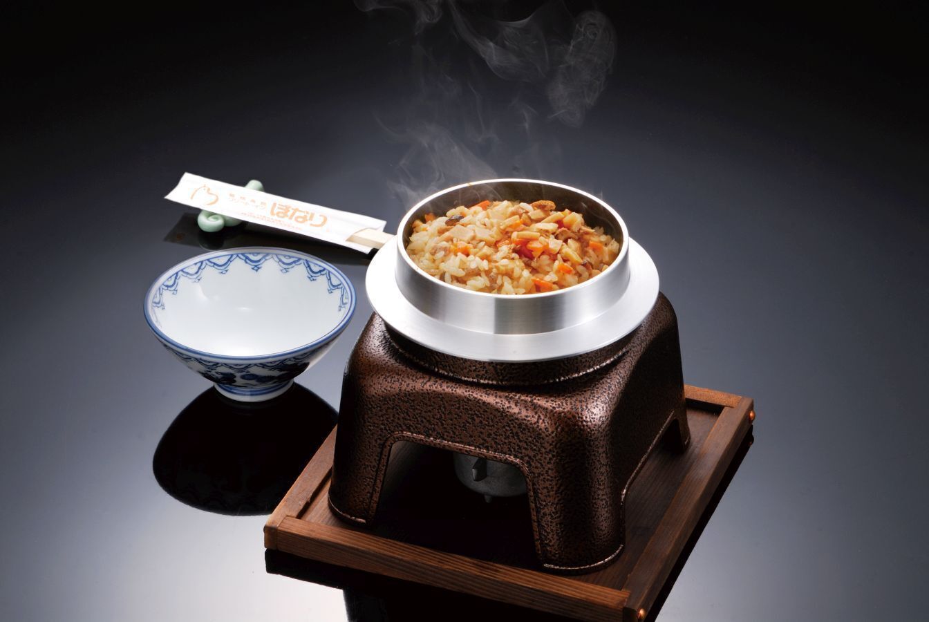 Uma configuração tradicional de panela japonesa, com uma tigela de cerâmica e um suporte de madeira.