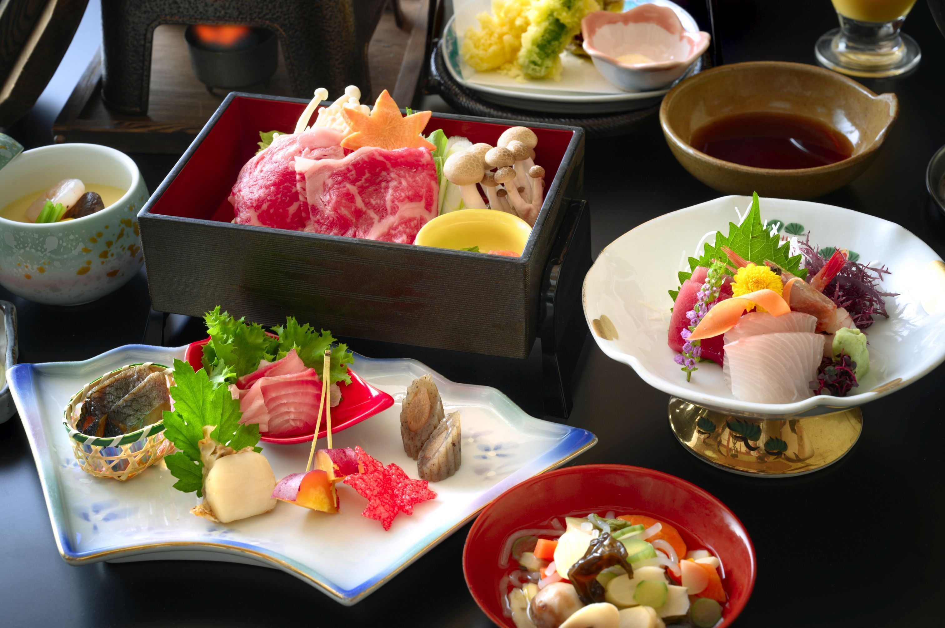 Diversos pratos em uma mesa, incluindo sushi, sashimi e outras iguarias, indicando uma experiência gastronômica.
