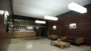 Uma área de recepção com balcão, dois sofás, uma mesa de centro e iluminação pendente moderna.
