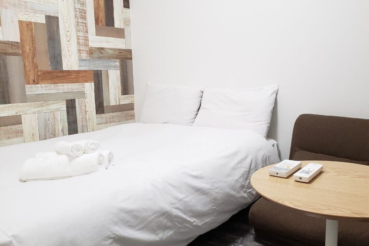 Quarto de hotel com uma cama, uma mesa de madeira redonda e um sofá marrom.