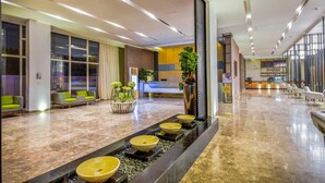 Um lobby de hotel moderno com balcão de recepção, área de estar e um elemento decorativo de água.