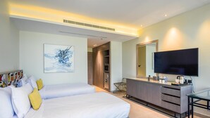 Quarto de hotel moderno com uma cama grande, televisão de tela plana, armário embutido e um pequeno espaço de estar.