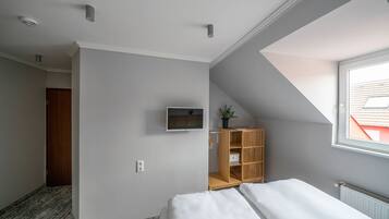 Quarto com uma cama, televisão, armário de madeira e janela.
