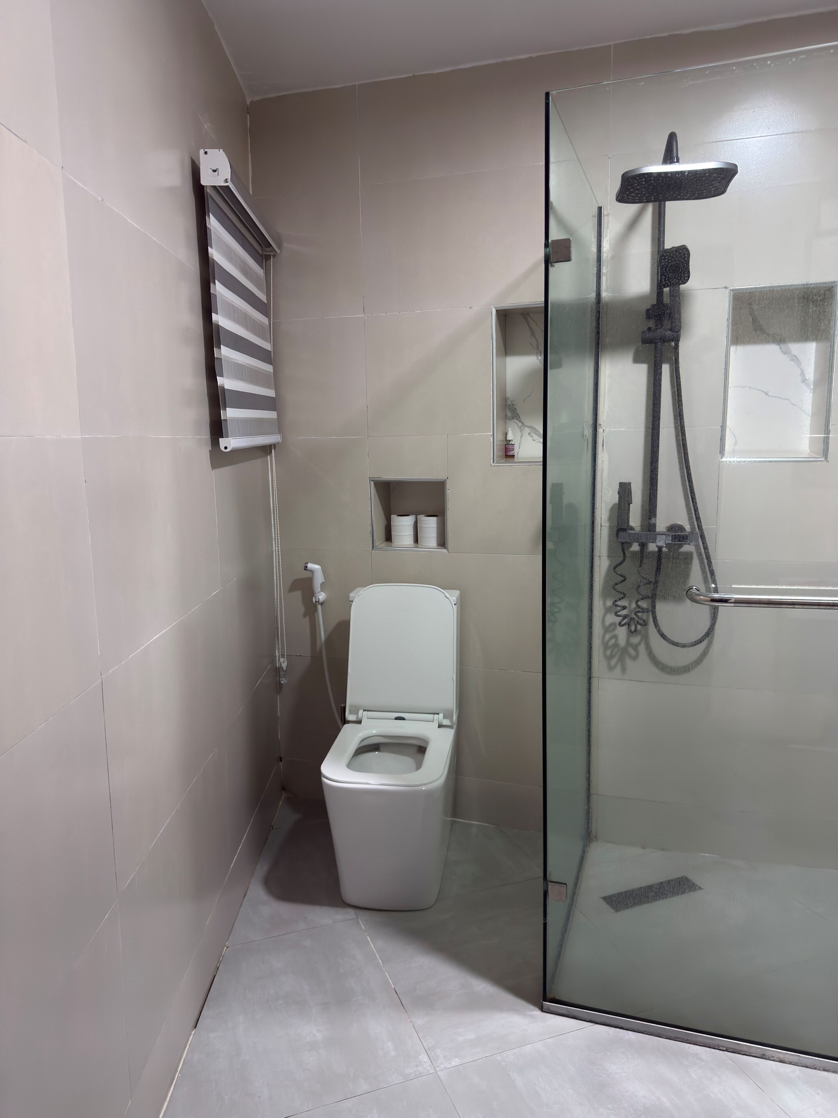 Um banheiro com vaso sanitário, chuveiro com box de vidro e porta-toalhas.