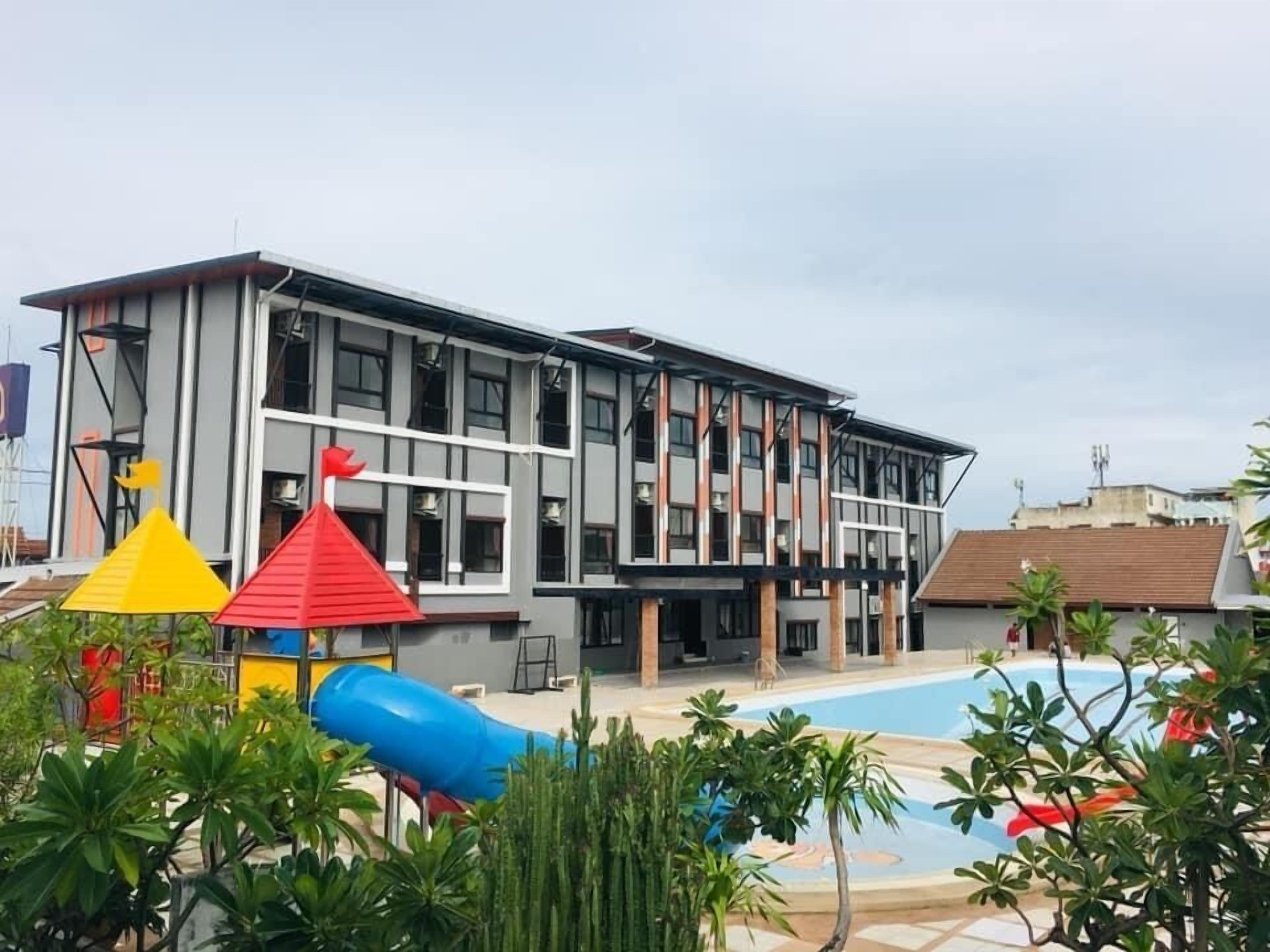 Um edifício moderno com área de piscina, incluindo um escorregador e guarda-sóis.