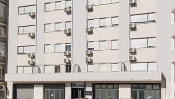 Um edifício de vários andares com vários carros estacionados na frente.