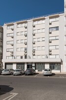 Um edifício de vários andares com vários carros estacionados na frente.