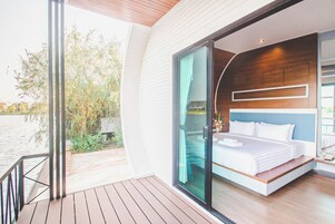 Quarto moderno com uma grande porta de vidro que dá para uma varanda com vista para um corpo d'água.
