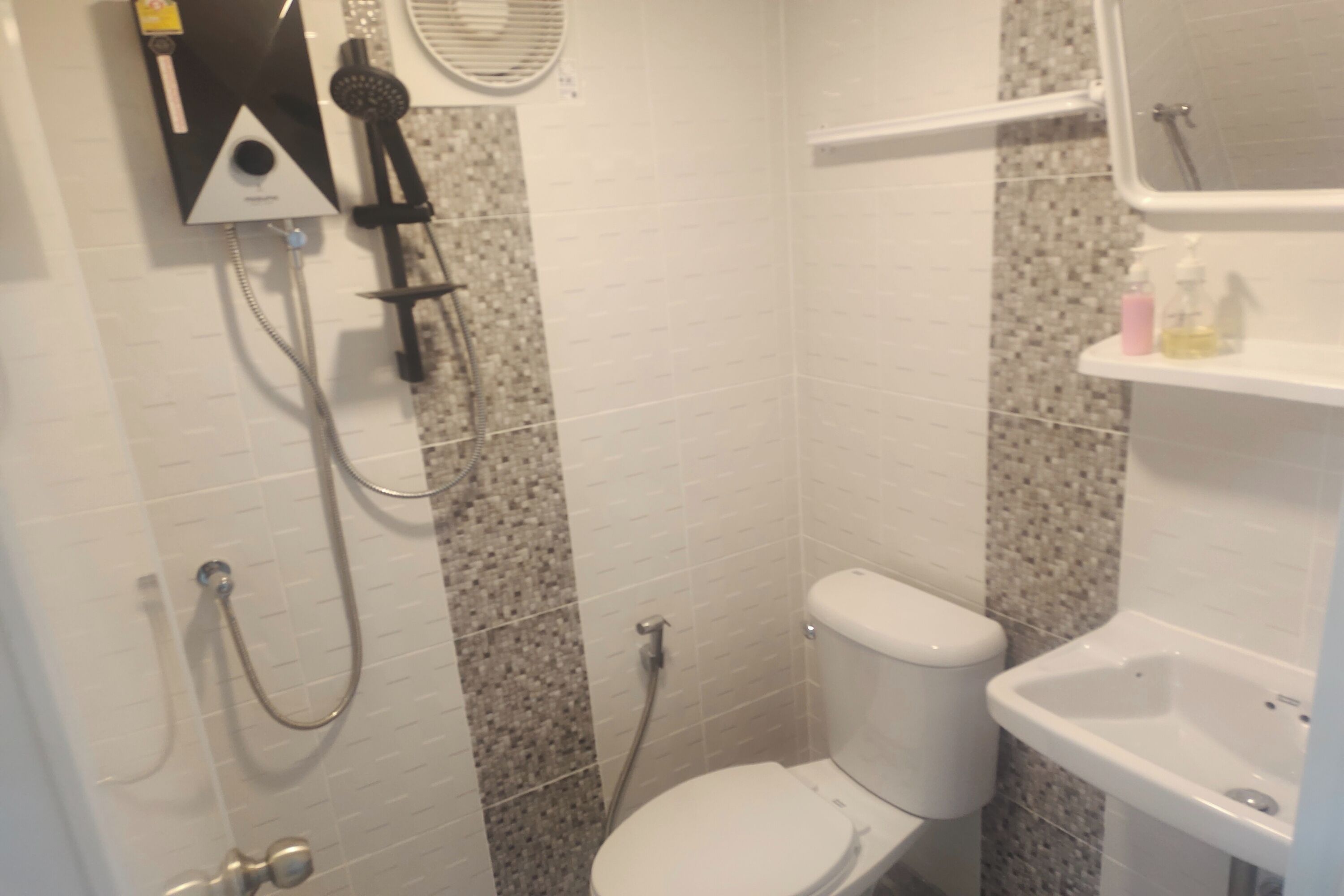 Casa de banho com sanita, chuveiro e lavatório.