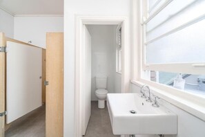 Casa de banho com lavatório branco, sanita e janela.
