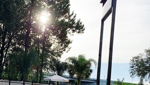 Piscina com escada de metal, cercada por uma grade, e área de estar externa com guarda-sóis.