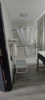 Um banheiro com chuveiro, porta-toalhas e pia.