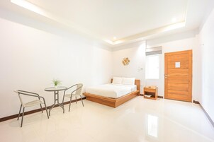 Quarto moderno com uma cama, duas cadeiras, uma mesinha e uma porta de madeira.