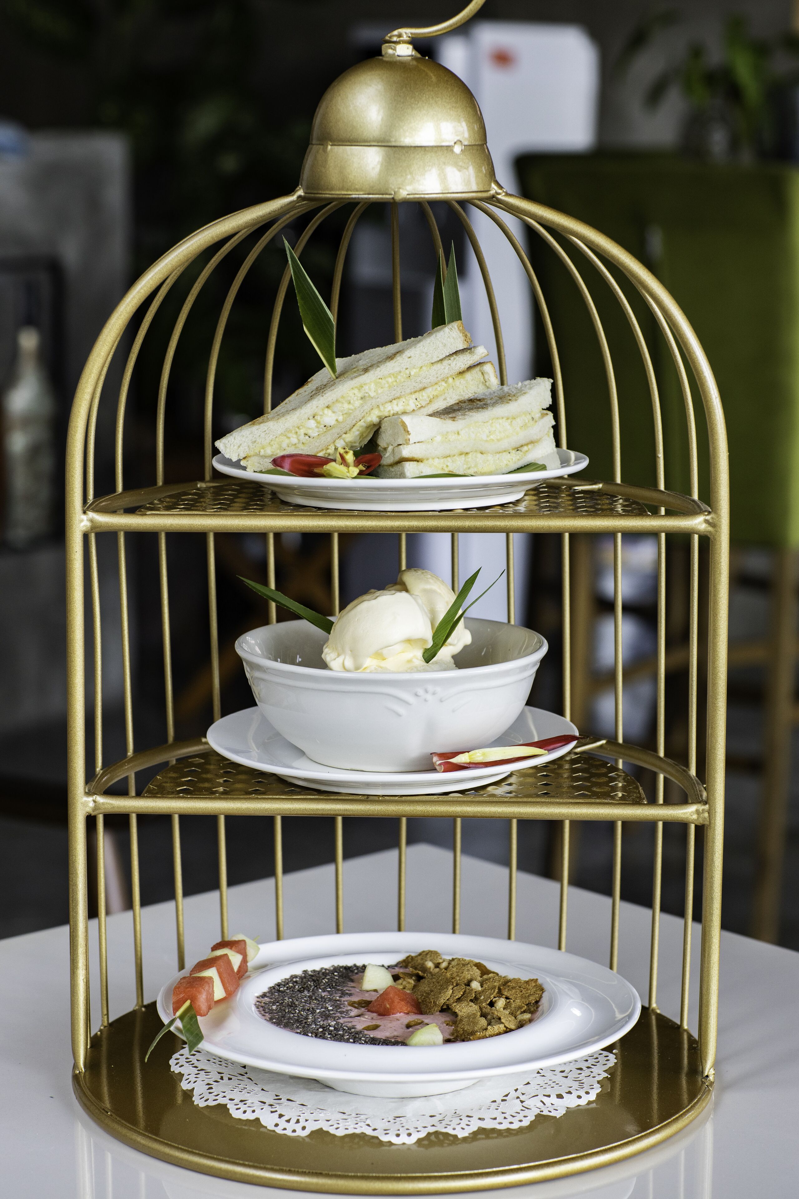 Suporte dourado em três níveis com alimentos.