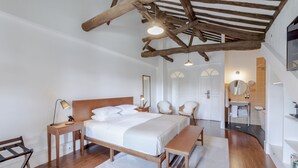 Quarto com cama de madeira, mesas de cabeceira, um banco e teto rústico.