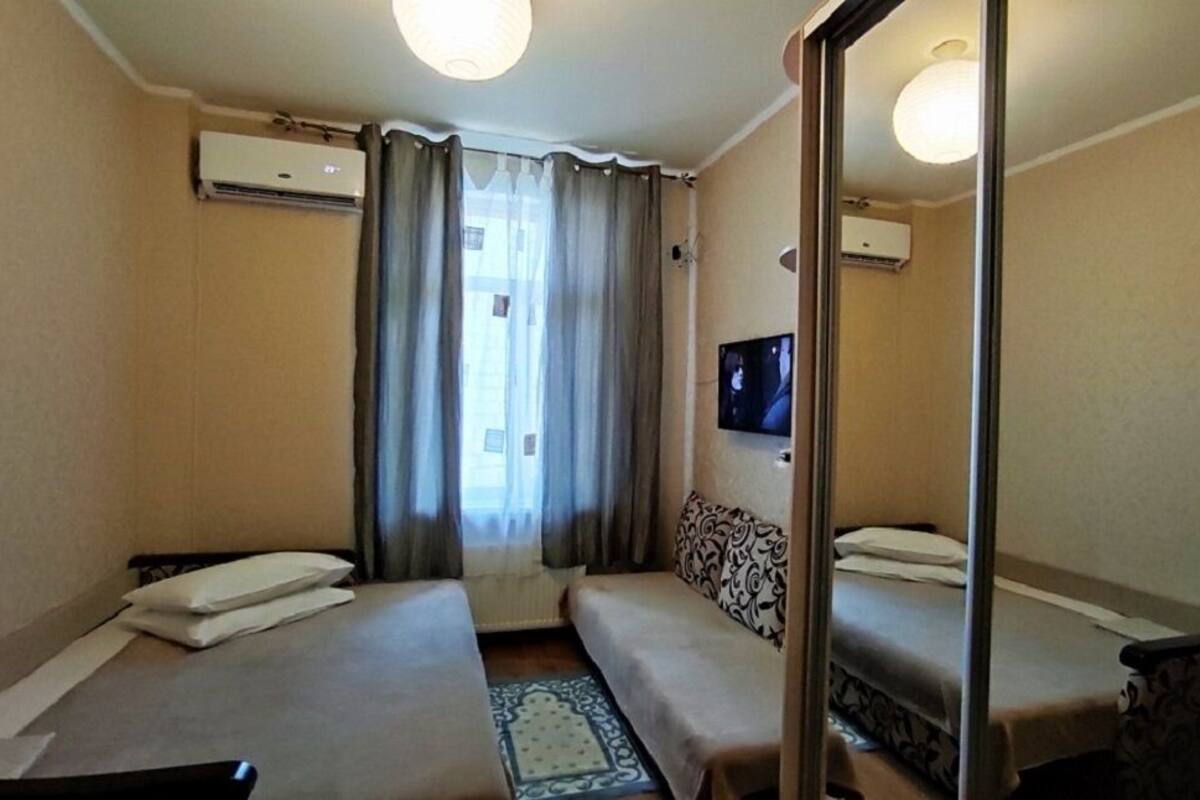 Quarto de hotel com duas camas de solteiro, um sofá, uma televisão e um aparelho de ar condicionado.