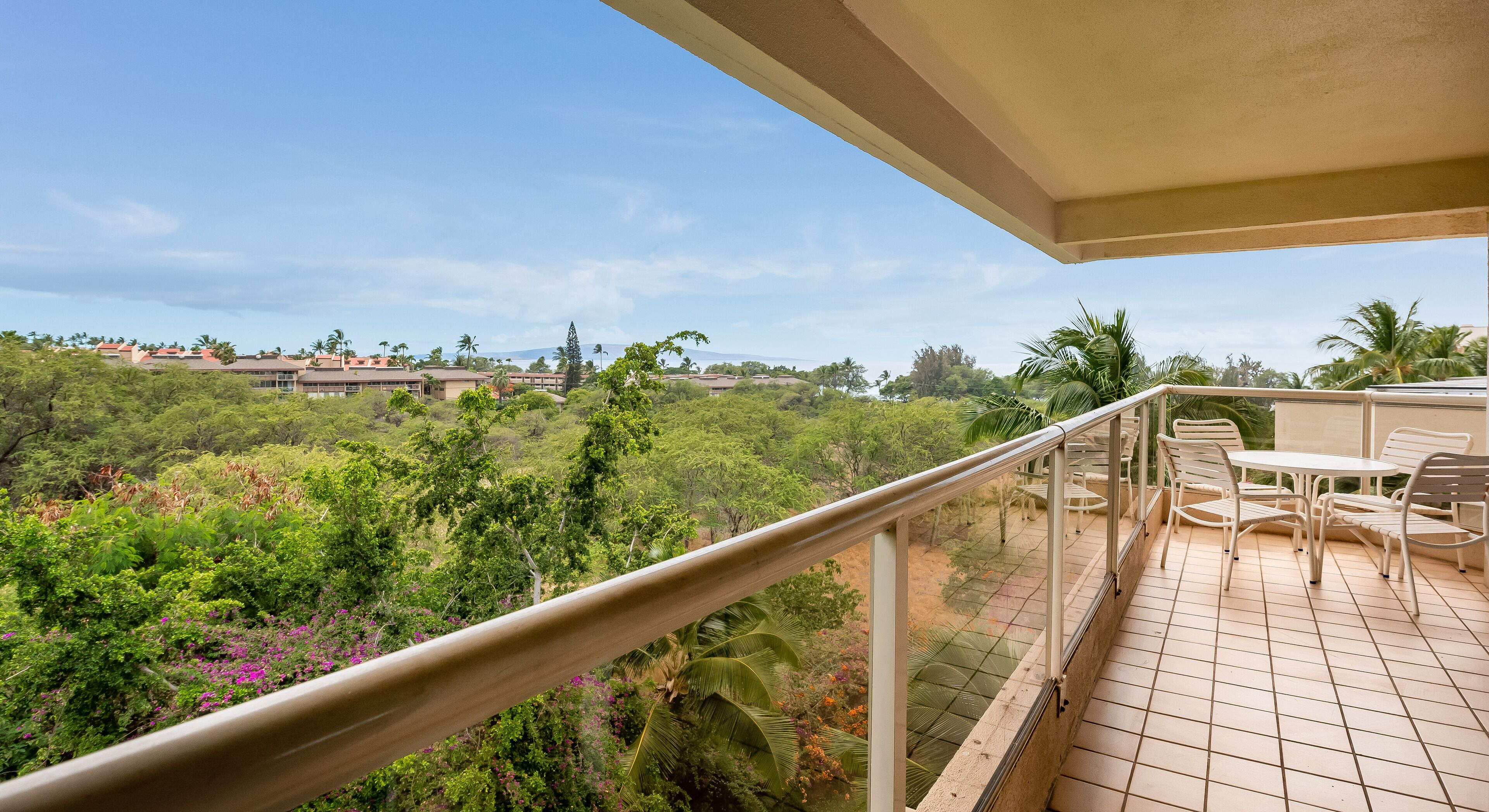 Uma varanda com vista para uma paisagem exuberante, incluindo árvores e edifícios ao longe.