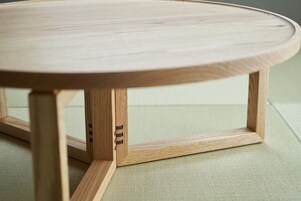 Uma mesa de madeira com tampo redondo e design simples e robusto.