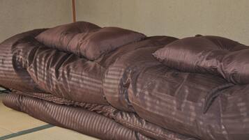 Uma cama futon bem arrumada com várias almofadas e um cobertor listrado.