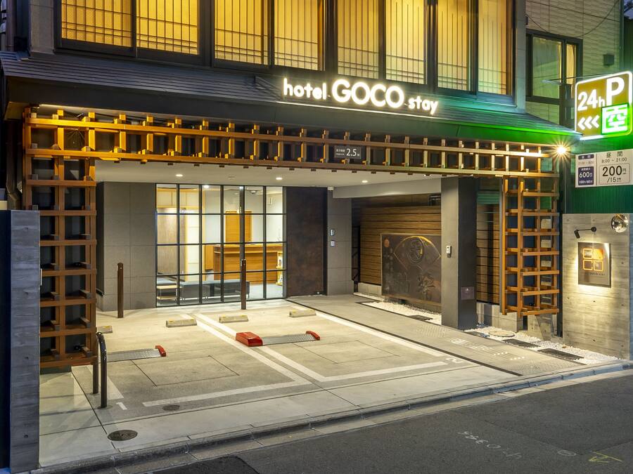 Entrada de hotel com uma placa indicando 'hotel Goco stay' e um aviso de estacionamento 24 horas.