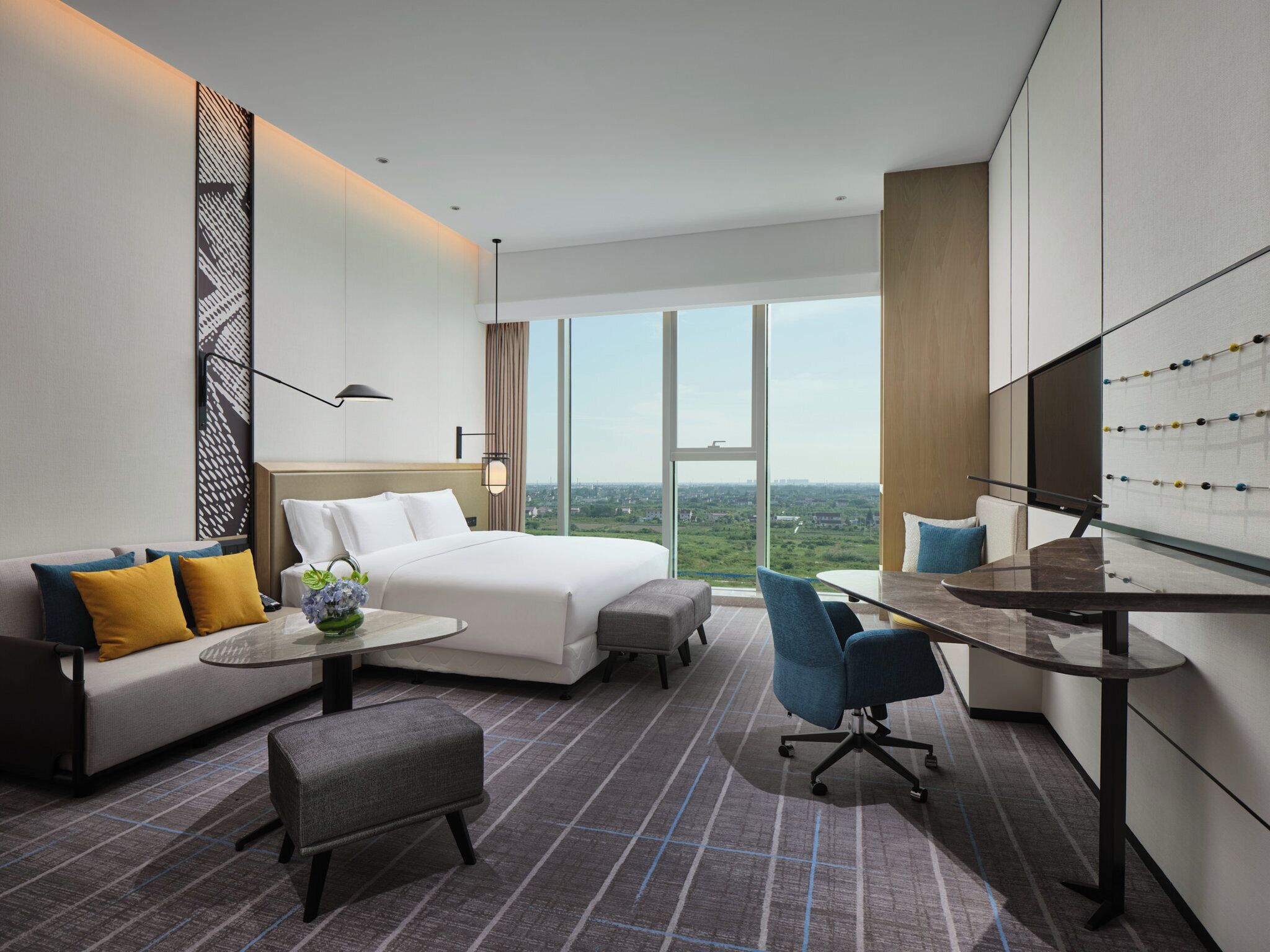 Quarto de hotel com cama, sofá, escrivaninha e uma cadeira.