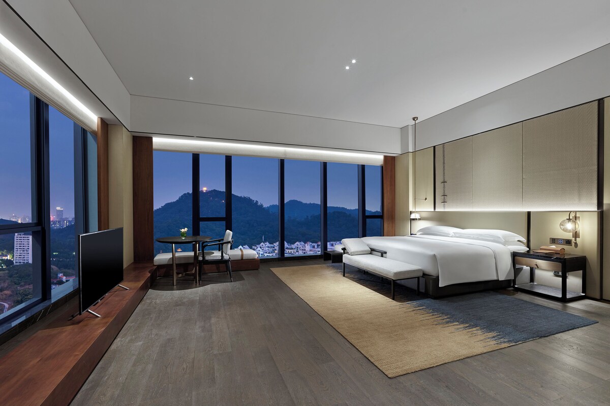 Quarto de hotel moderno com uma cama grande, uma escrivaninha e uma televisão.
