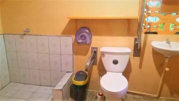 Casa de banho com sanita, lavatório e um contentor de lixo.