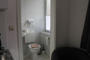 Casa de banho pequena e compacta com sanita, lavatório e janela.