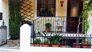 Um edifício com toldo branco, portão e plantas em vasos no alpendre.