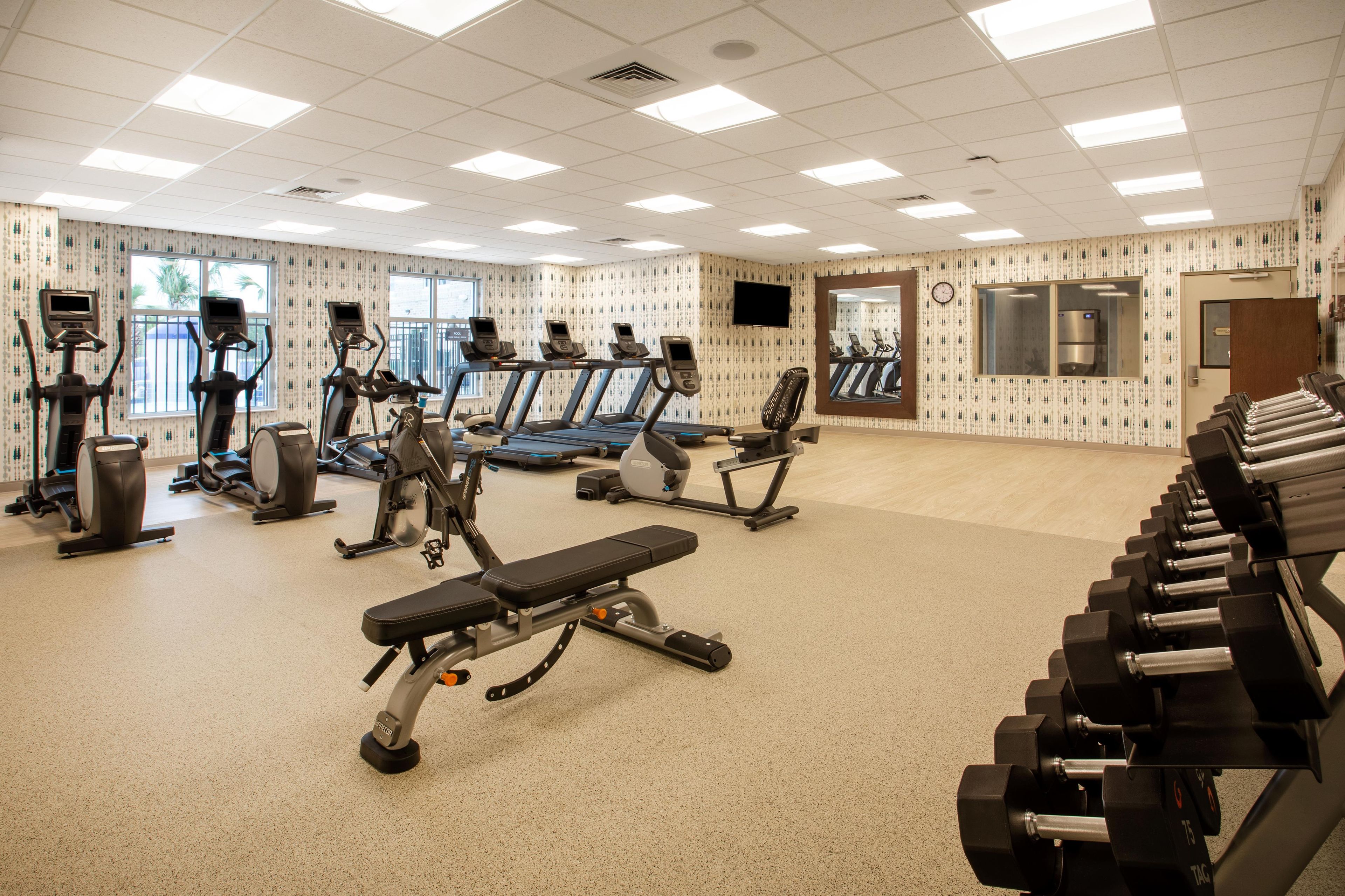 Uma academia com diversos equipamentos de exercícios, incluindo esteiras, bicicletas ergométricas e aparelhos de musculação.