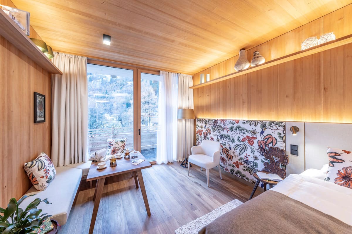 Um quarto aconchegante com paredes e teto de madeira, uma mesa de jantar com cadeiras, um sofá e uma cama.