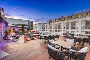 Um bar no terraço com área externa e vista para o horizonte da cidade.
